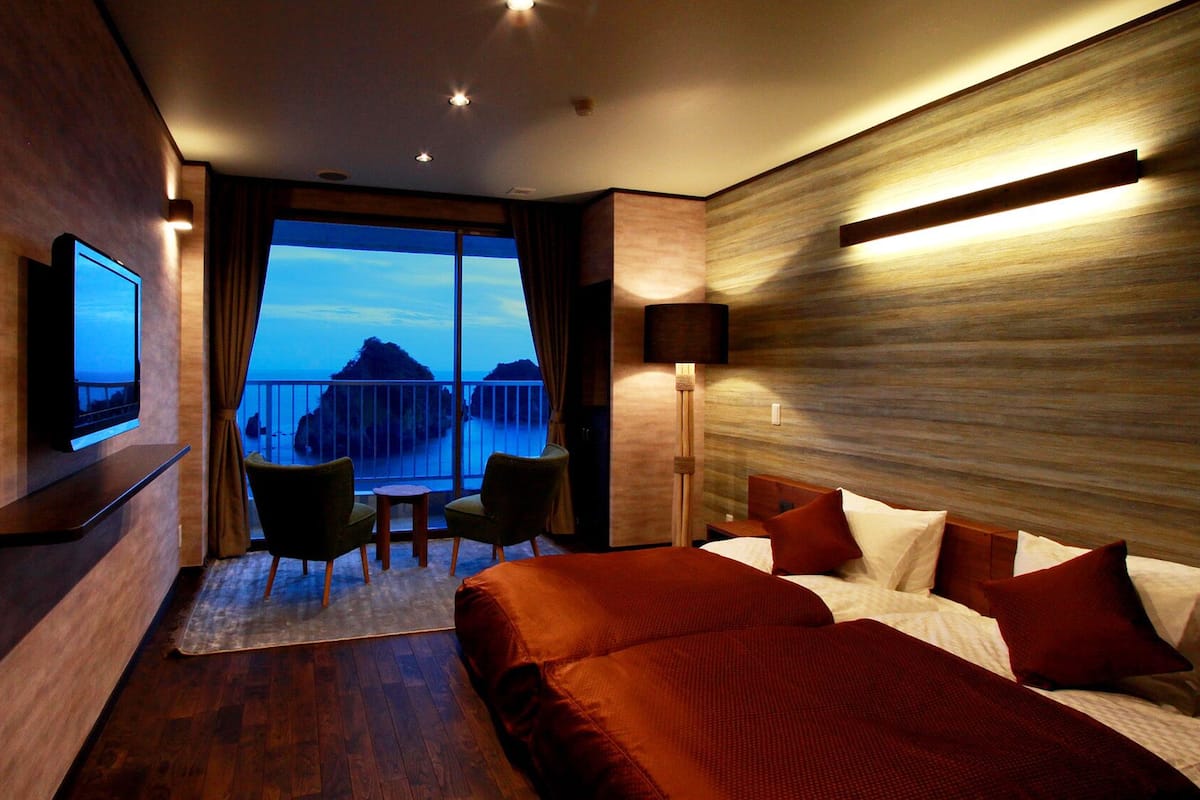 Quarto de hotel com cama, televisão, varanda e uma mesa de trabalho.