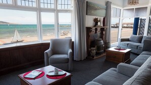 Sala de estar com uma grande janela com vista para a praia, lareira e um conjunto de sofás.