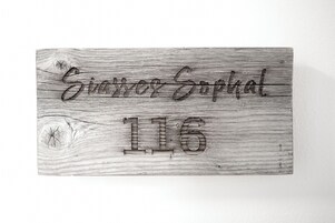 Uma placa de madeira com o texto 'Simmons Spaqual 116' entalhado.
