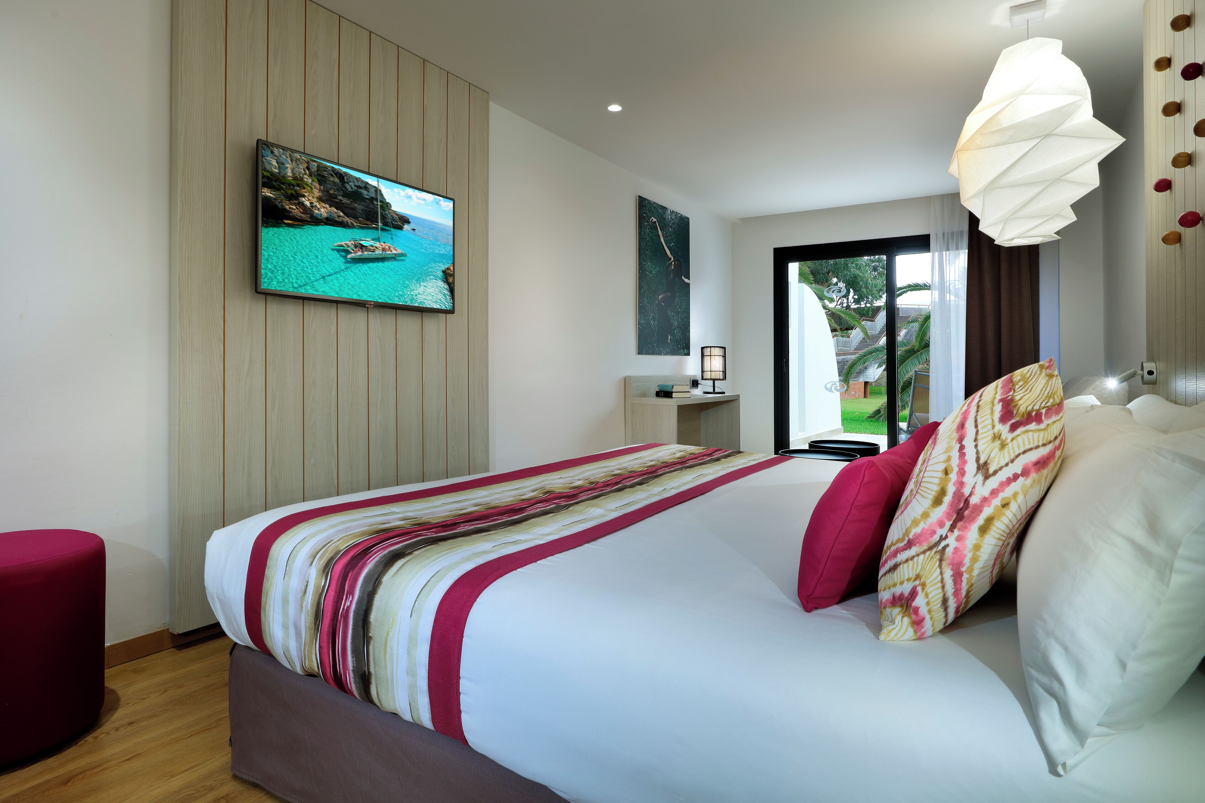 Quarto de hotel moderno com uma cama grande, TV de tela plana, escrivaninha e vista para o exterior.