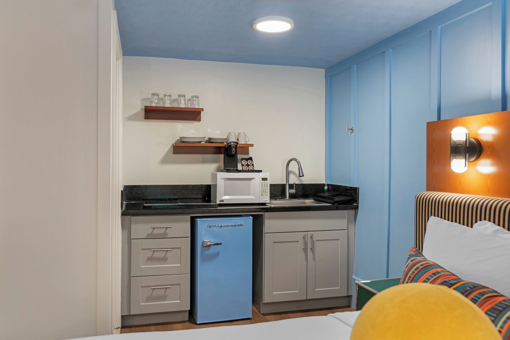 Uma kitchenette compacta equipada com micro-ondas, cafeteira e mini-frigorífico.