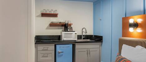 Uma kitchenette compacta equipada com micro-ondas, cafeteira e mini-frigorífico.