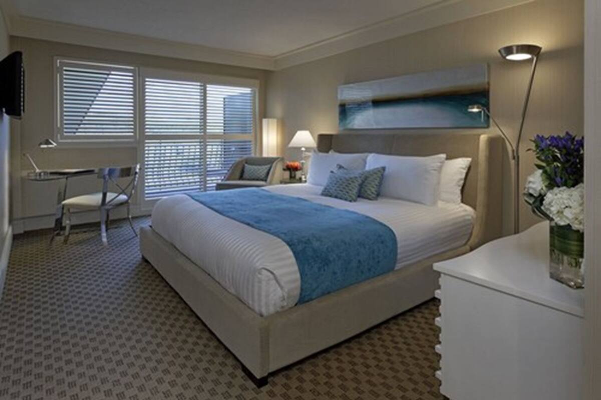 Quarto de hotel com uma cama grande, uma escrivaninha e uma cadeira.
