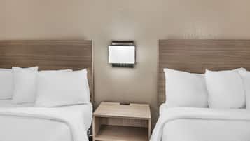 Quarto de hotel com duas camas, uma mesa de cabeceira e painel de controlo na parede.