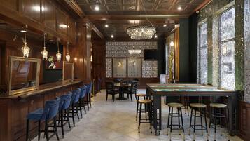 Uma área de bar com painéis de madeira, mesa de bilhar e banquetas.