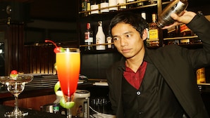 Um bar com um bartender servindo uma bebida num copo.
