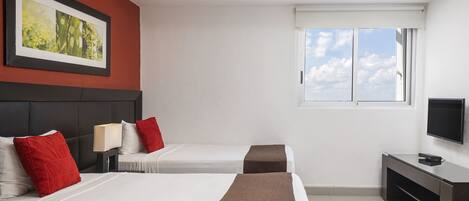 Quarto de hotel com duas camas, televisão, janela com vista e um quadro na parede.