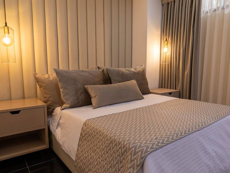 Quarto moderno com uma cama grande, uma mesa de cabeceira e um aplique na parede.