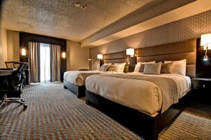 Quarto de hotel com duas camas, uma escrivaninha e uma cadeira.