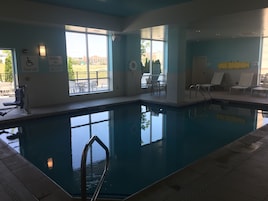 Uma piscina interior com janelas amplas, uma cadeira de salva-vidas e um elevador de piscina.