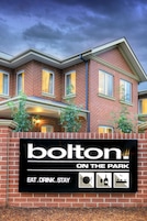 Um edifício de tijolos com uma placa que diz "bolton on the park" e ícones para comer, beber e hospedar.