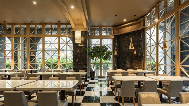 Interior de restaurante moderno, com piso quadriculado, janelas amplas e iluminação pendente.