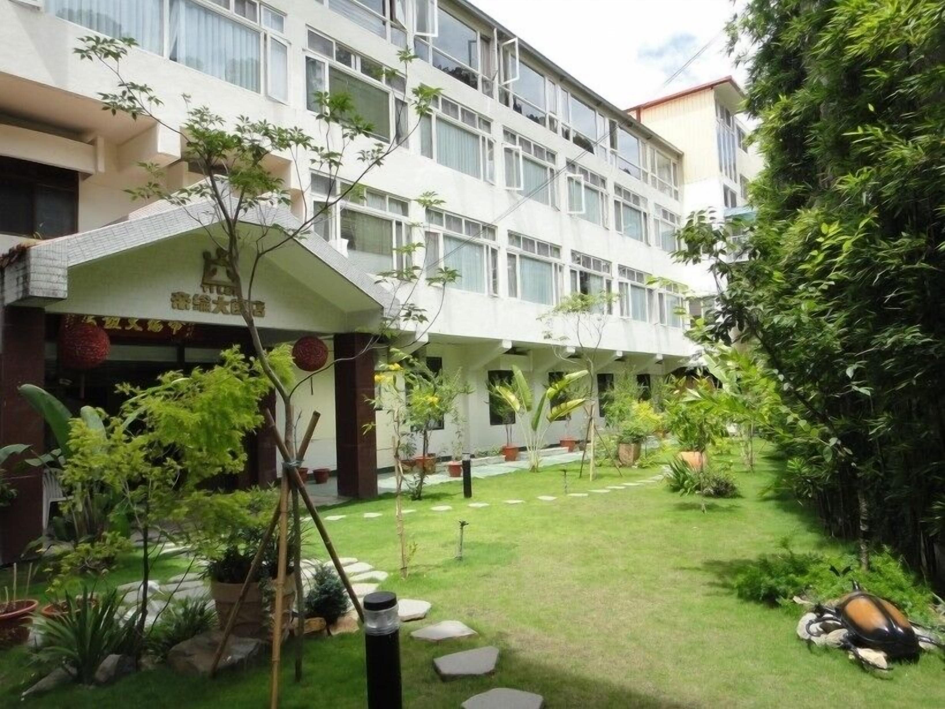 Um hotel com um pátio ajardinado, plantas em vasos e céu claro.
