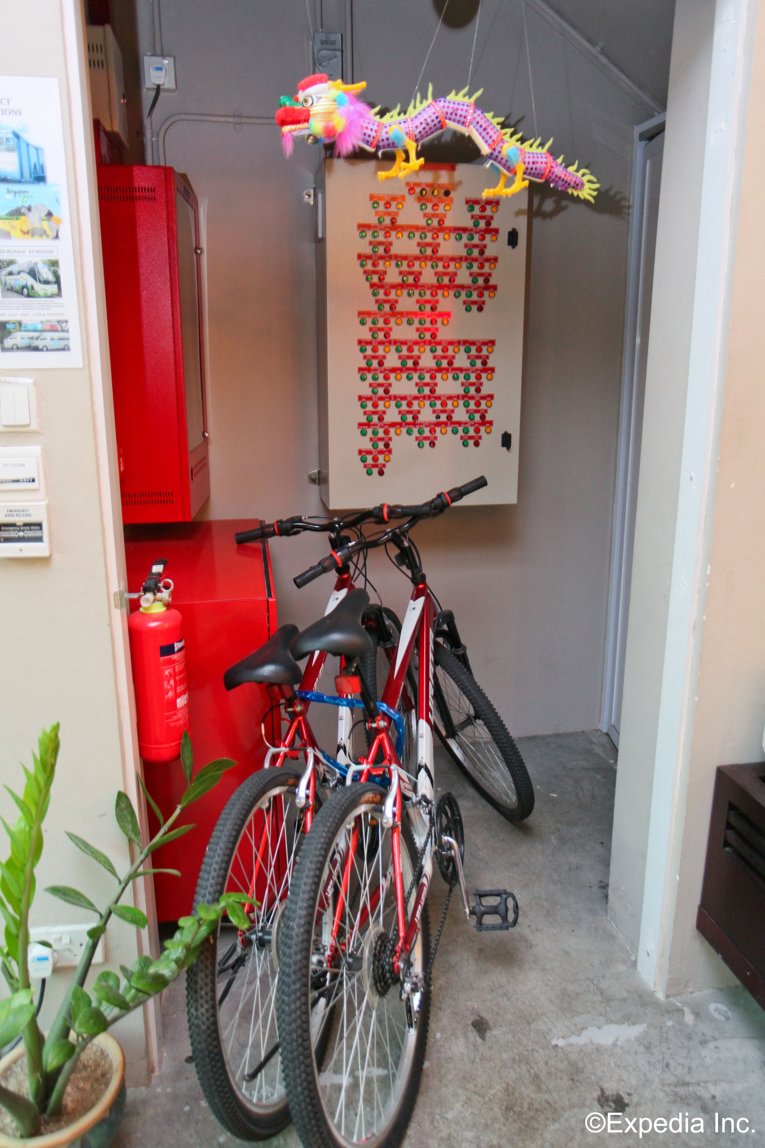 Um corredor estreito com um armário vermelho, uma bicicleta e um dragão decorativo pendurado no teto.