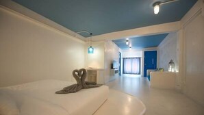 Quarto de hotel moderno com uma cama grande, uma escrivaninha e vista para o quarto vizinho.