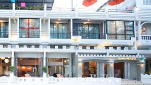 Um hotel de vários andares com design arquitetônico moderno, apresentando varandas, janelas amplas e áreas de estar ao ar livre.