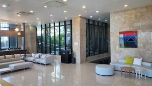 Um lobby amplo com design moderno, apresentando uma área de estar com sofás e um espaço para café.