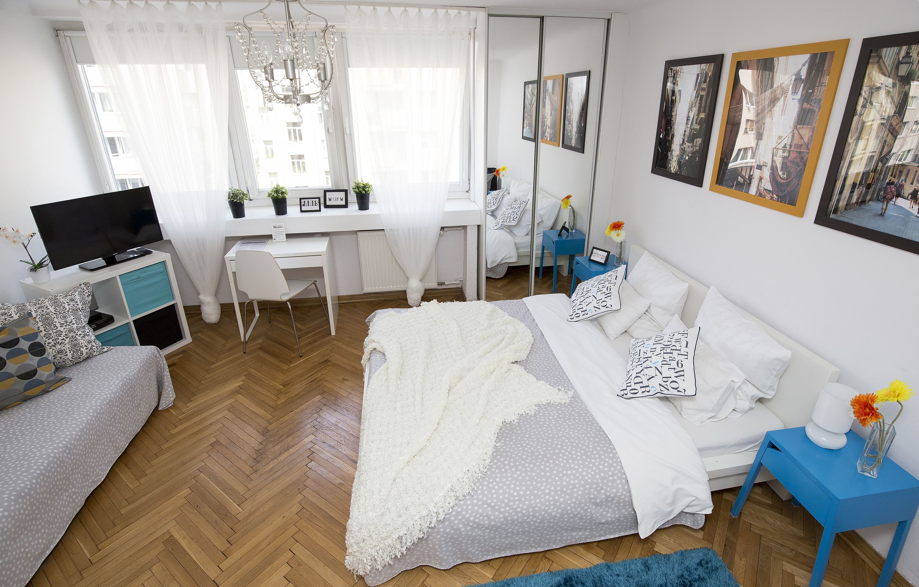 Quarto moderno com uma cama grande, uma escrivaninha, uma televisão e uma cadeira.