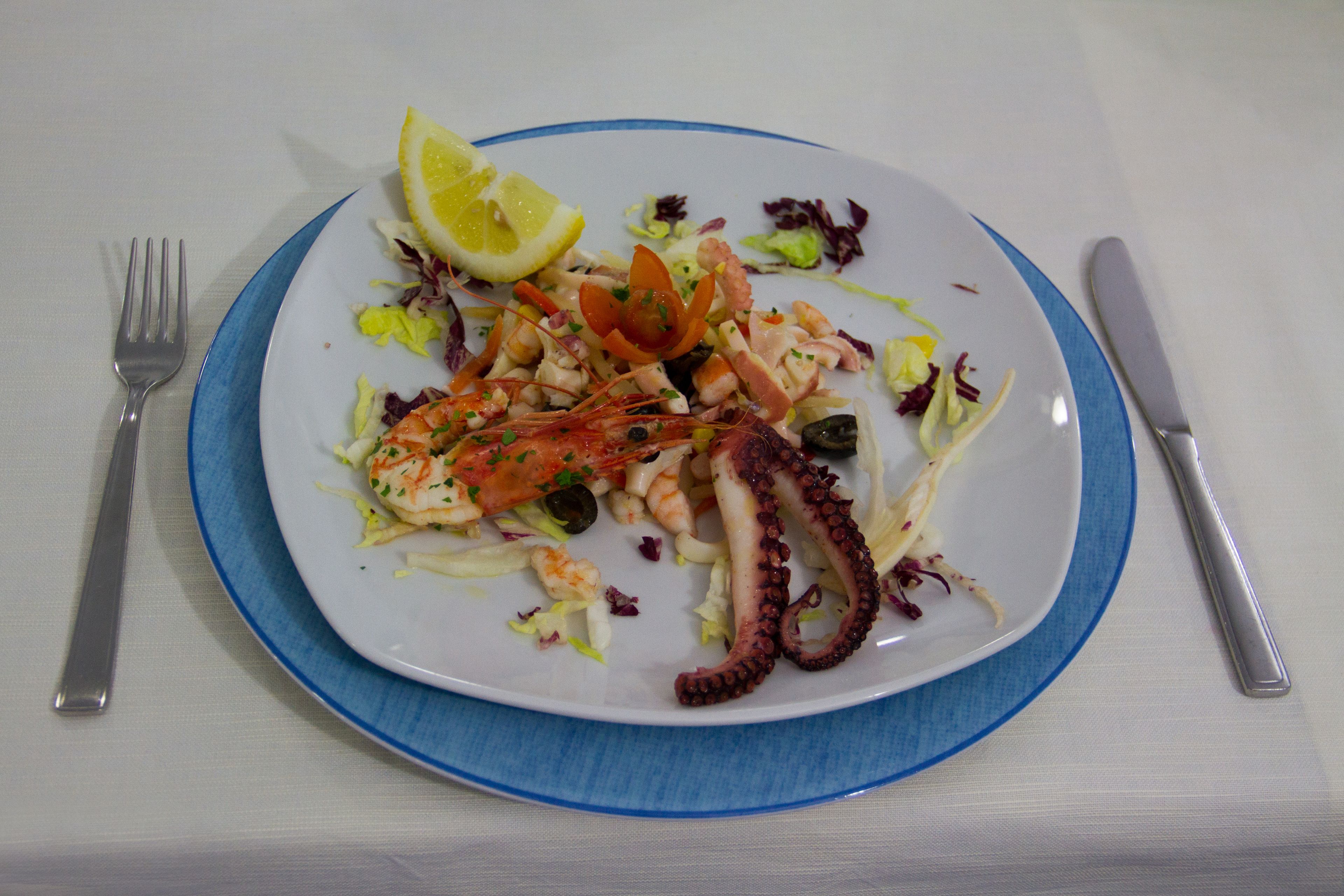 Uma salada de mariscos com limão e caranguejo, apresentada numa travessa azul.