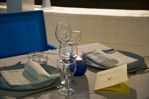 Mesa posta com copos transparentes, uma vela e um cardápio.
