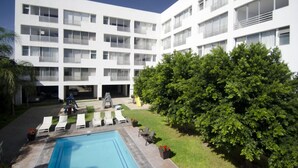 Um edifício moderno com piscina, espreguiçadeiras e um jardim bem cuidado.