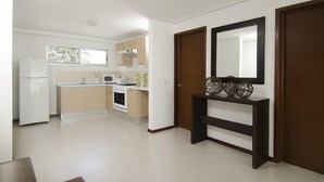 Uma cozinha moderna com eletrodomésticos brancos, armários de madeira e um aparador escuro com objetos decorativos.
