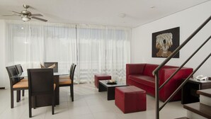 Uma sala de estar moderna com um sofá vermelho, cadeiras pretas, uma mesa de vidro e uma escada.