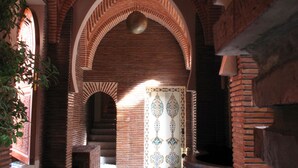 Um interior com soalho em mosaico, arcos de tijolo e porta estampada.