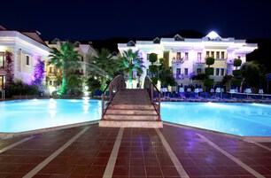Piscina com degraus que levam a um edifício com várias varandas e fachada bem iluminada.