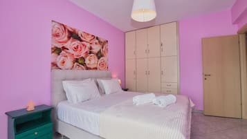 Quarto com cama, mesa de cabeceira, guarda-roupa e parede rosa com um mural floral.