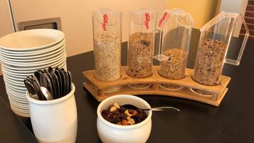Disposição para o café da manhã com várias tigelas de cereal e uma tigela de mix de castanhas.