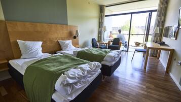Quarto de hotel com duas camas, uma escrivaninha e uma cadeira.