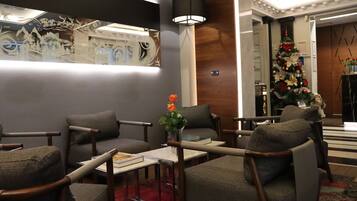 Um lobby moderno com balcão de recepção, área de estar e um pinheiro de Natal.