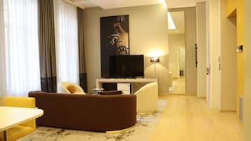 Suíte grand, 1 quarto | Área de estar | TV de tela plana 32 polegadas com canais a cabo, TV