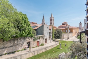 Uma praça histórica com edifícios de pedra, uma igreja e uma estátua.