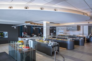 Disposição moderna de buffet com várias estações de serviço, divisória de vidro e grande variedade de alimentos.