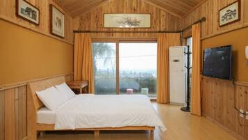 Quarto com painéis de madeira, uma cama, televisão e frigorífico.