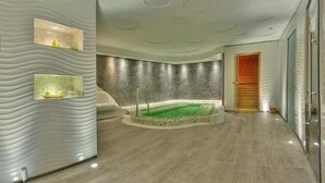 Um spa moderno com uma banheira grande, paredes texturizadas e iluminação embutida.