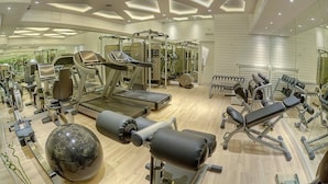 Academia moderna com diversos equipamentos de exercício, incluindo esteiras, máquinas de peso e uma grande bola de ginástica.