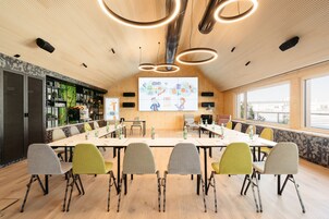 Uma sala de conferência com uma mesa grande, cadeiras e uma tela de apresentação.