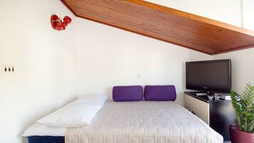 Quarto com cama, televisão e planta.