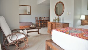 Um quarto com uma cama, uma cômoda de madeira, uma poltrona de balanço, uma mesa de madeira e um espelho.