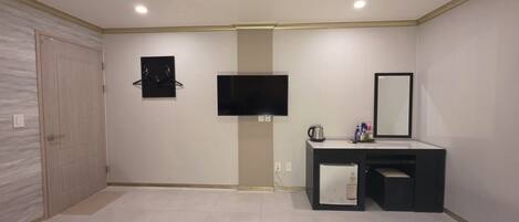 Casa de banho moderna com televisão de ecrã plano, espelho e pequeno armário.