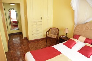 Quarto com cama, cadeira, mesa de cabeceira e guarda-roupa.