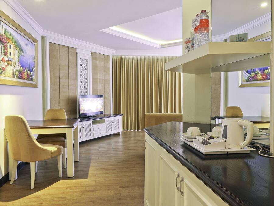 Quarto de hotel moderno com área de jantar, televisão, cafeteira e minibar.
