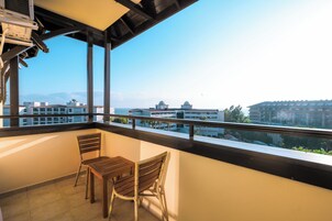 Uma varanda com mesa e cadeiras de madeira, com vista para um horizonte urbano com edifícios e céu limpo.