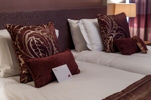 Quarto de hotel com cama, almofadas e um cartão sobre a cama.