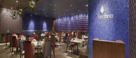 Um restaurante com parede azul e balcão de recepção de madeira com a inscrição 'krishna'.