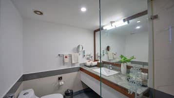 Uma casa de banho moderna com sanita, lavatório e espelho.