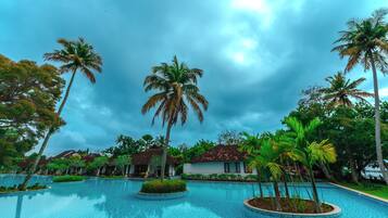 Um resort com uma piscina grande, palmeiras e edifícios em estilo tradicional.